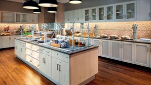 Uma cozinha moderna com ilha central, armários brancos e piso de madeira.