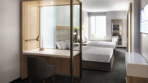 Quarto de hotel moderno com uma escrivaninha, duas camas, um espelho grande e vista para a cidade.