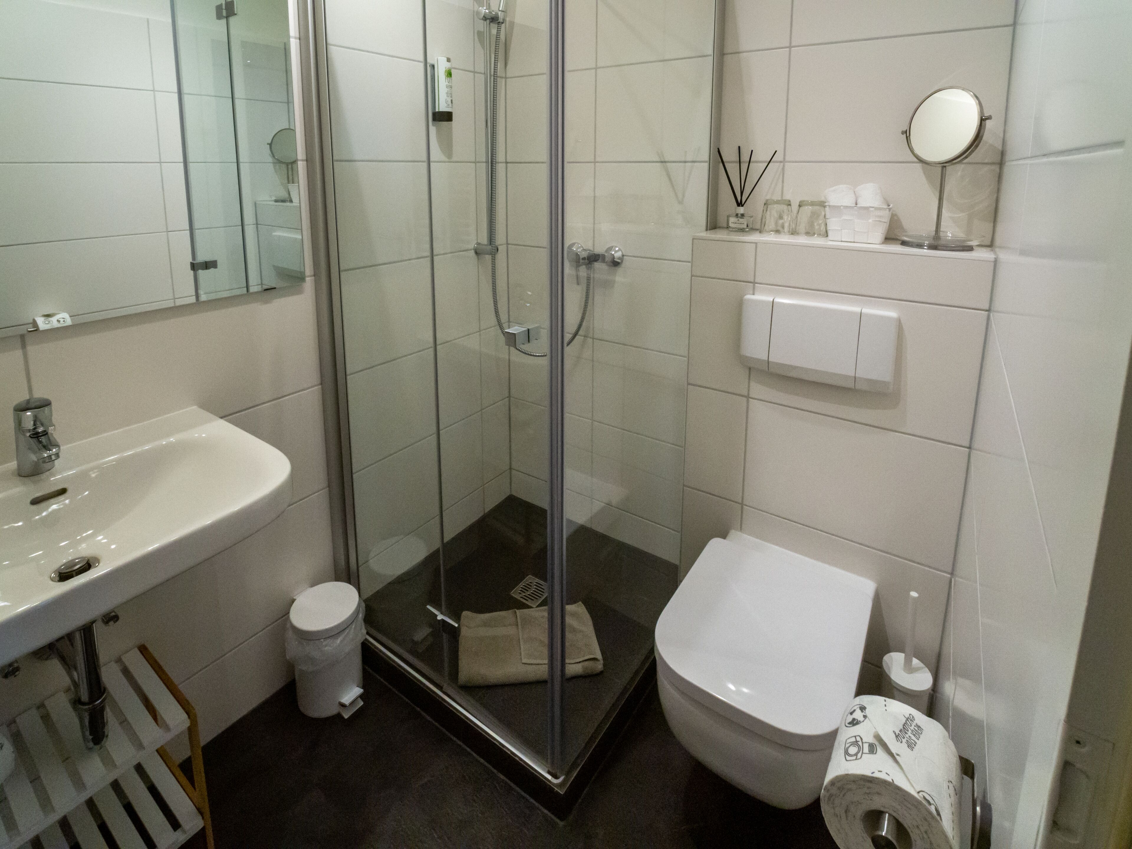 Uma casa de banho moderna com cabine de duche envidraçada, lavatório branco e sanita.