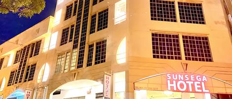 Um hotel de vários andares com um destaque para o letreiro 'Sunsega Hotel'.