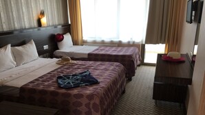 Quarto de hotel com duas camas, uma escrivaninha e uma televisão.