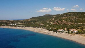Uma área costeira com praia, edifícios e uma colina.