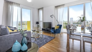 Uma sala de estar moderna com sofá, TV e área de refeições.