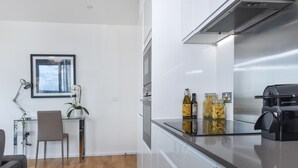 Uma cozinha moderna com armários brancos, um exaustor de aço inoxidável e uma cafeteira.