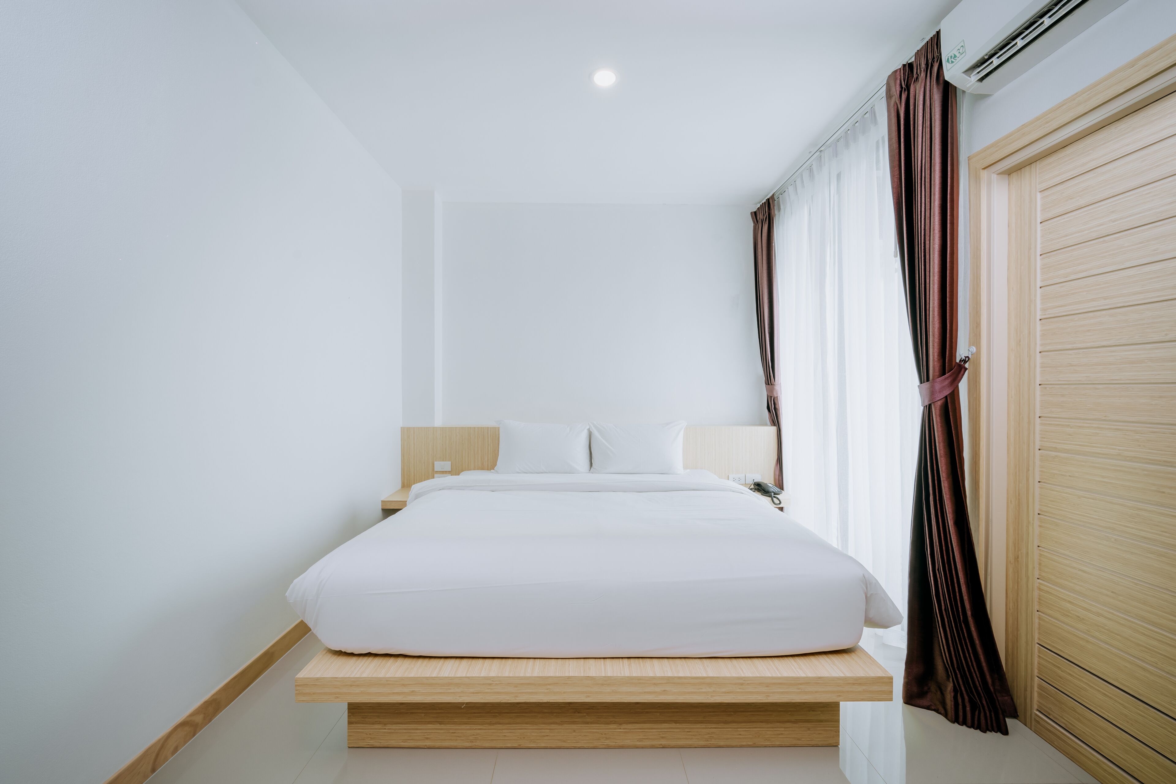 Quarto moderno com cama, mesas de cabeceira e guarda-roupa de madeira.