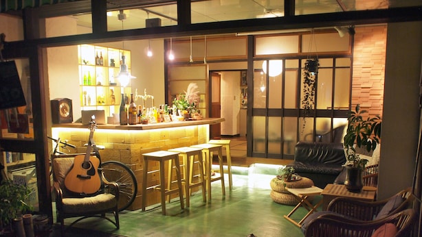 Um espaço de bar acolhedor, com banquetas, um violão e um balcão.