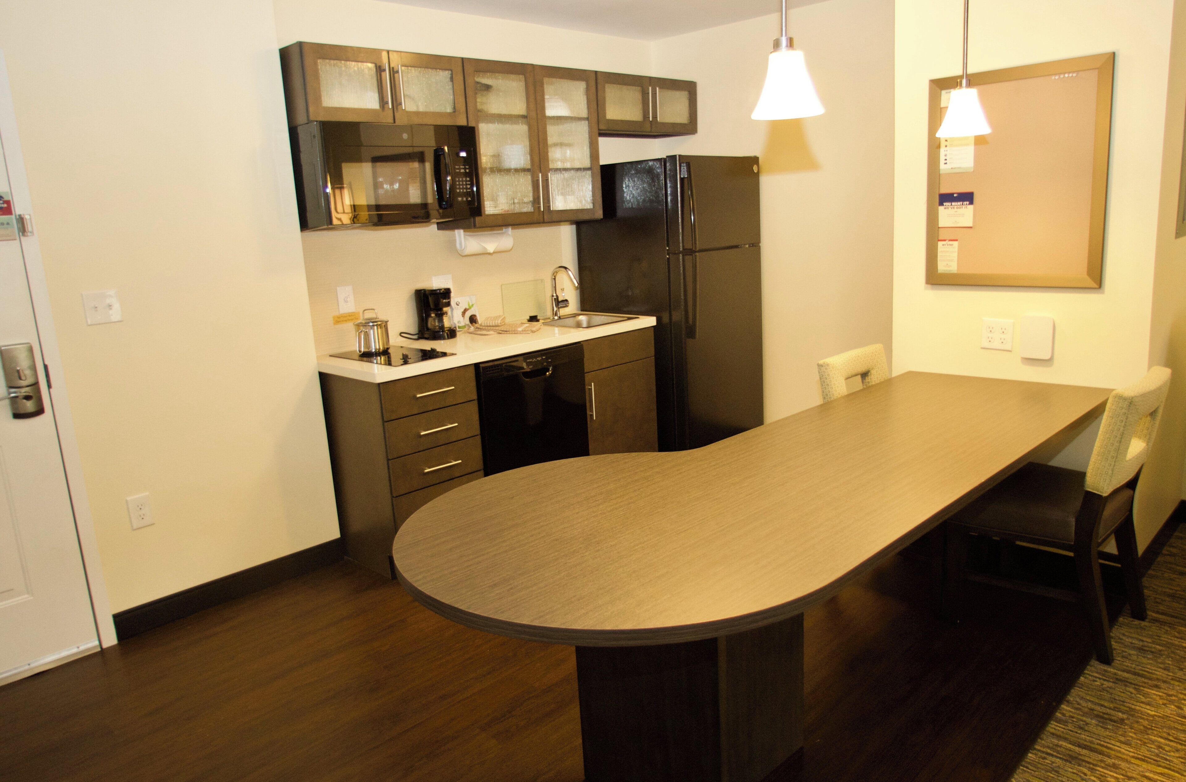 Cozinha moderna com uma ilha grande, eletrodomésticos de aço inoxidável e um espaço de jantar com mesa e cadeiras de madeira.