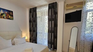 Quarto com uma cama grande, televisão de tela plana, espelho e um quadro na parede.