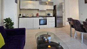 Uma sala de estar moderna com uma mesa de centro de vidro, um sofá roxo e uma área de jantar com cadeiras.