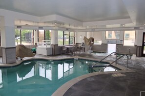 Piscina interna com chão ladrilhado, área coberta para descanso e grandes janelas.