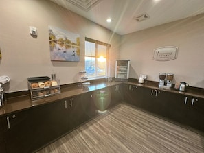 Cozinha moderna com ilha central, espaço para café e placa de café da manhã.