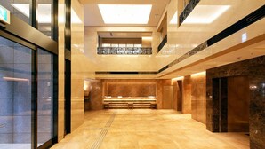 Um hall espaçoso com teto alto, piso de mármore e área de estar central.