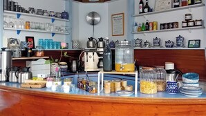 Uma área de bar com prateleiras cheias de garrafas, copos e potes.
