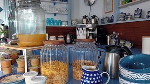 Uma bancada de cozinha com diversos alimentos e utensílios, incluindo potes, uma cafeteira e uma chaleira.