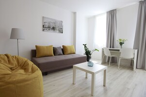 Uma sala de estar moderna com um sofá, uma mesa de centro e uma escrivaninha com cadeiras.