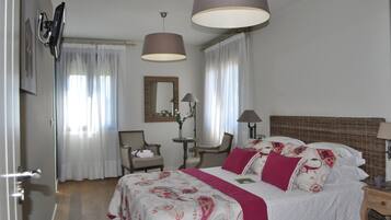 Quarto com cama, duas cadeiras, mesa, espelho e televisão.