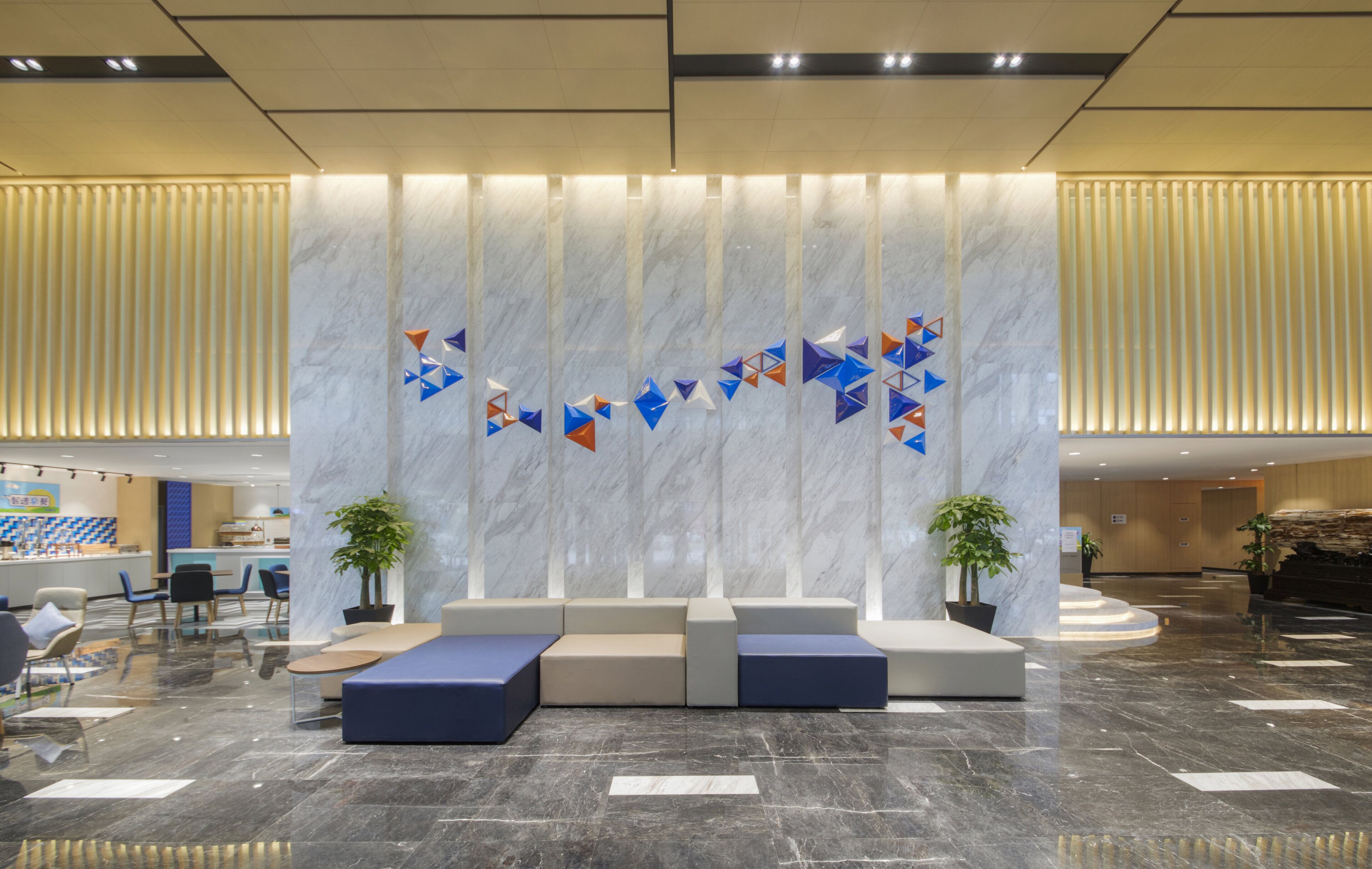Um lobby moderno com balcão de recepção, área de estar e painéis decorativos na parede.