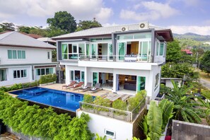 Uma moradia de dois andares com piscina, área de estar externa e placa de 'Venda/Aluguel'.