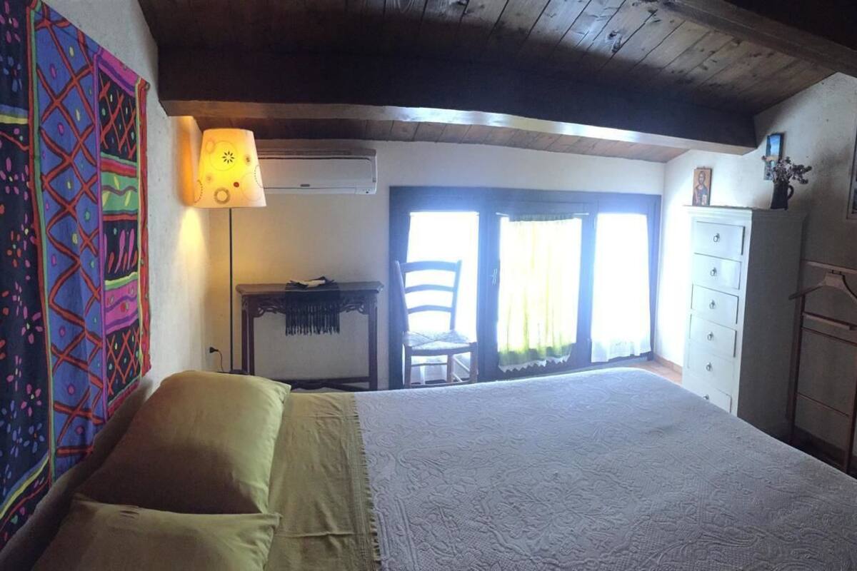 Um quarto com cama, escrivaninha, cadeira e guarda-roupa.
