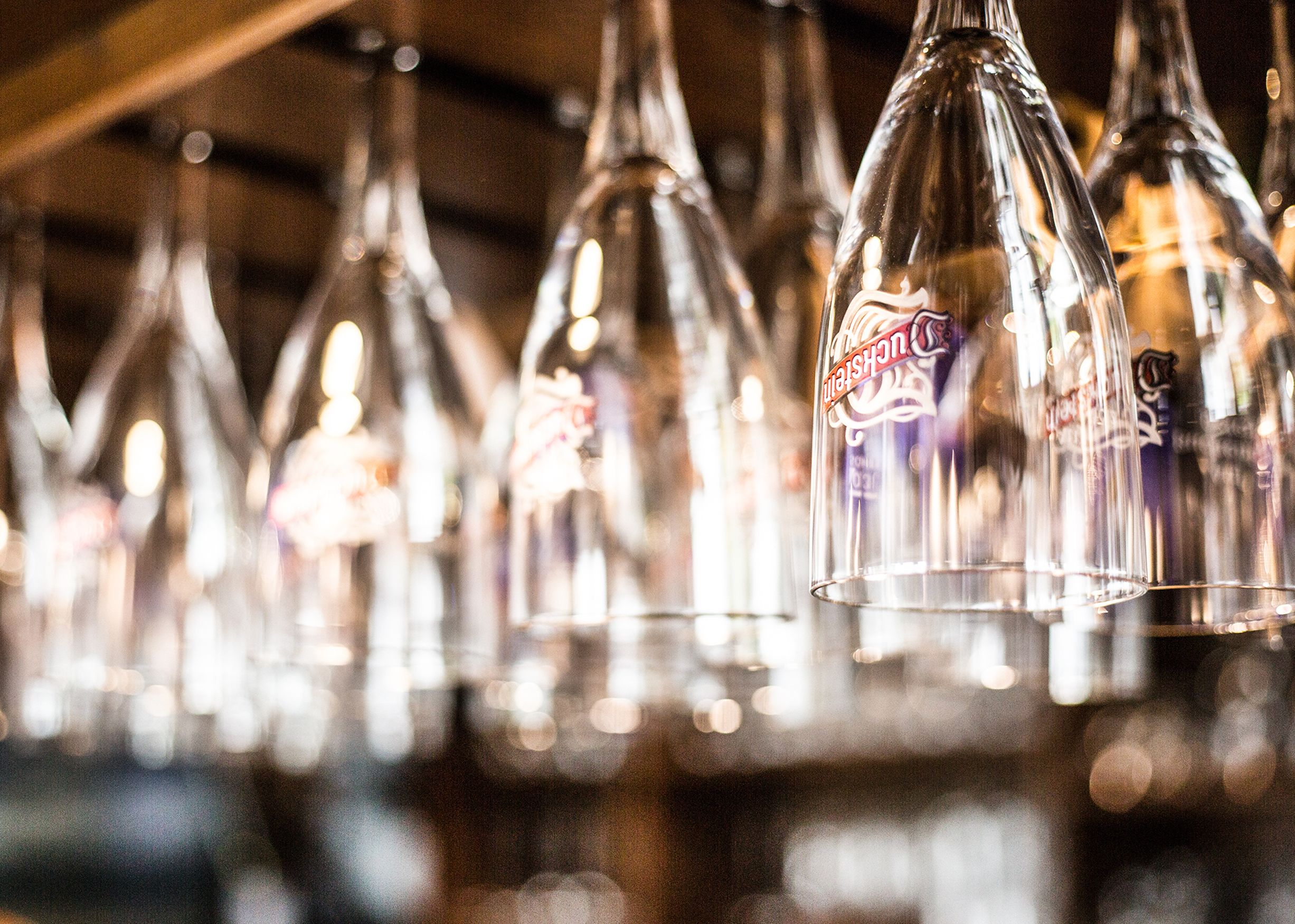 Vários copos de vinho vazios pendurados no teto.