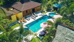Um imóvel residencial com piscina, espreguiçadeiras e jardim.