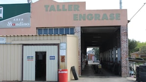 Um edifício com a placa 'TALLER ENGRASE' e um aviso indicando 'AREA Sandino'.