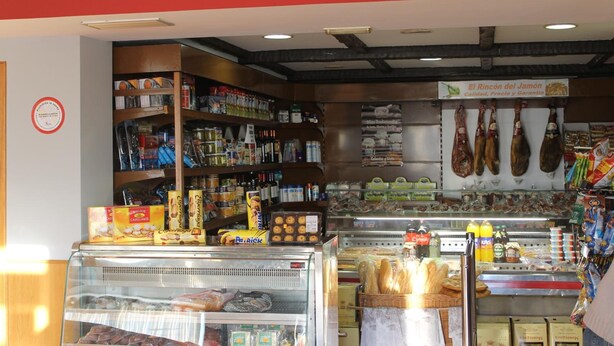 Uma padaria com prateleiras repletas de diversos produtos de panificação e uma vitrine com pães.