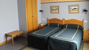 Quarto com cama de madeira, um pequeno banco de madeira, mesa de cabeceira e duas luminárias fixadas na parede.