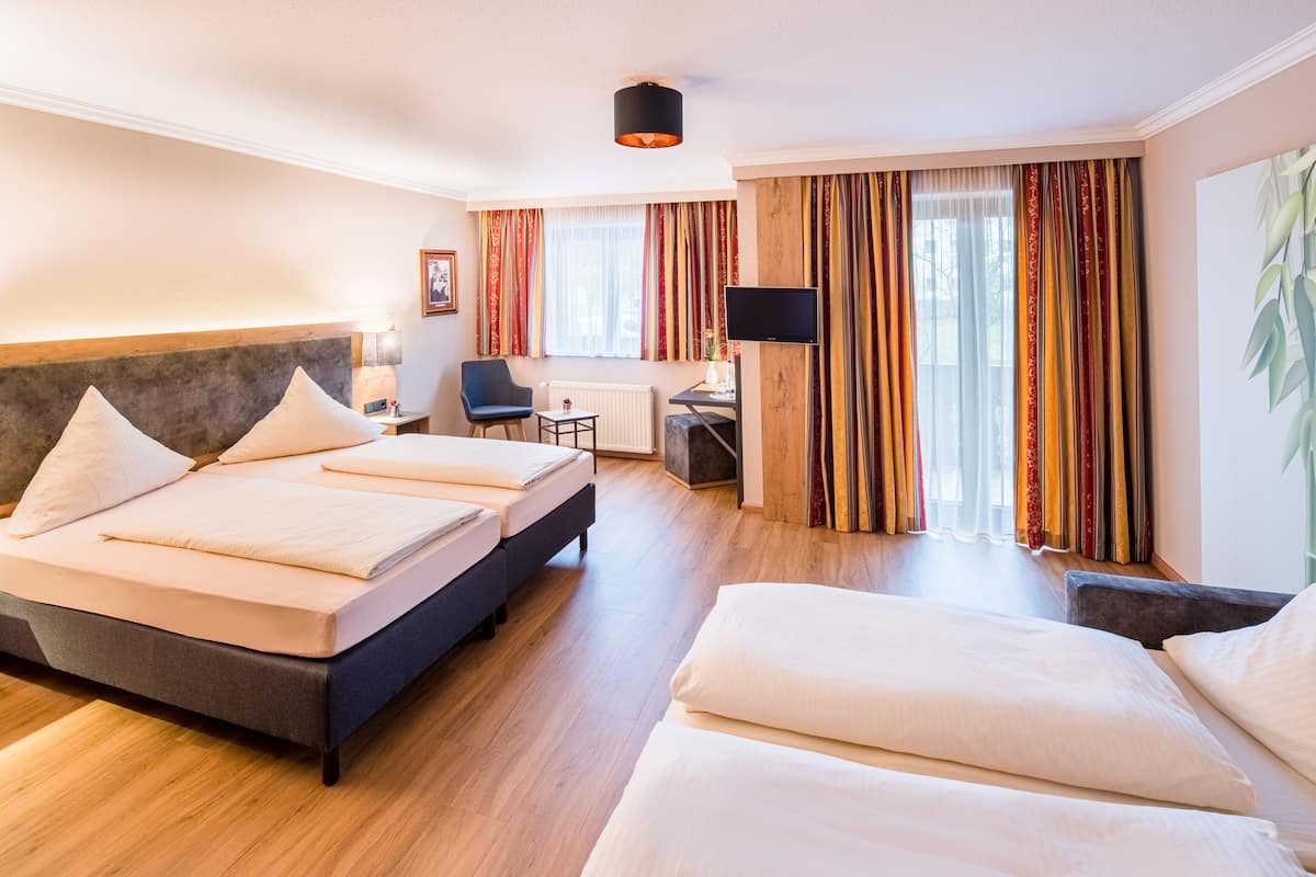 Quarto de hotel com uma cama grande, uma escrivaninha, uma cadeira e uma televisão.