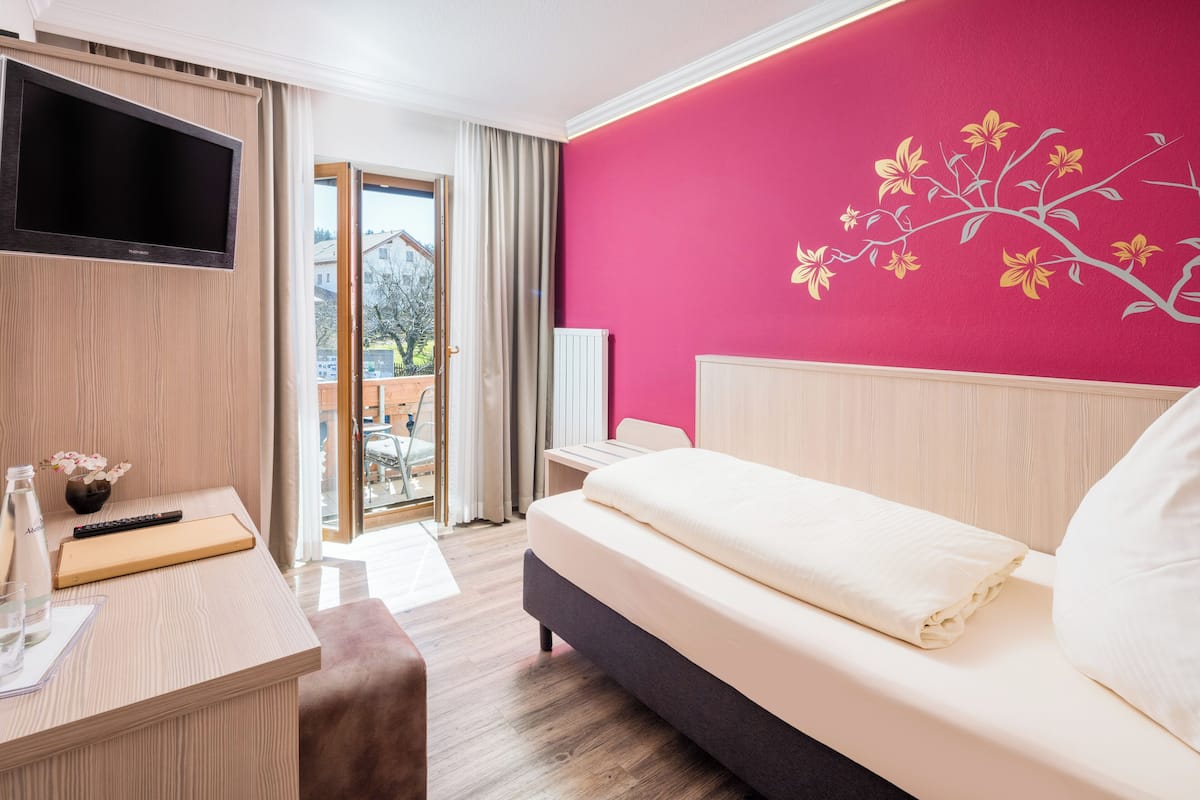 Quarto de hotel com cama, escrivaninha, televisão e vista para o exterior.