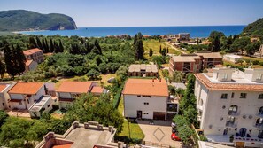 Uma área residencial costeira com casas em socalcos, uma praia e uma montanha ao fundo.