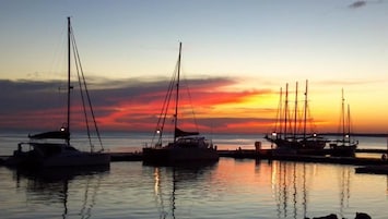 Marina com vários veleiros atracados ao pôr do sol.
