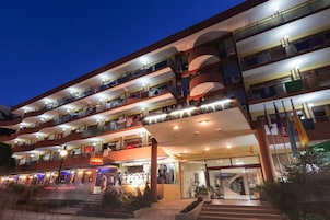 Um hotel com vários andares, varandas, um átrio central e área comercial no térreo.