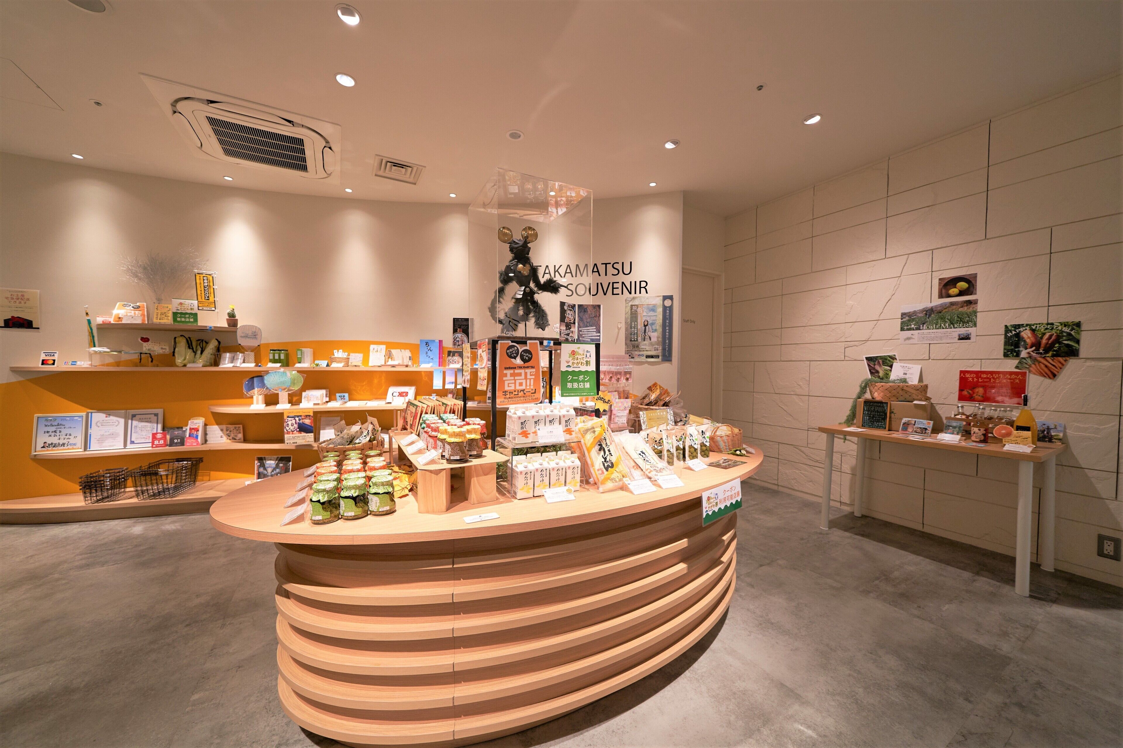 Um interior moderno com um balcão central de exposição, prateleiras com produtos e uma parede com cartazes informativos.