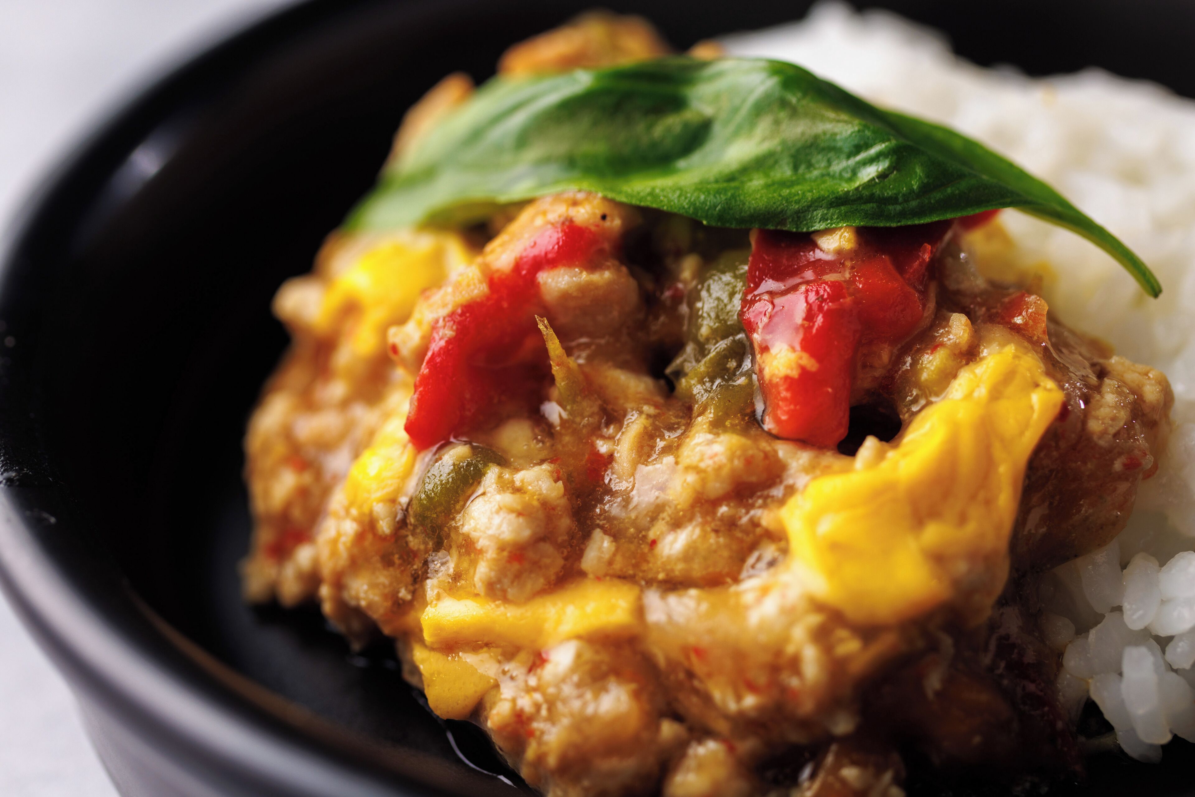 Uma tigela de curry com arroz e um enfeite de folha verde.