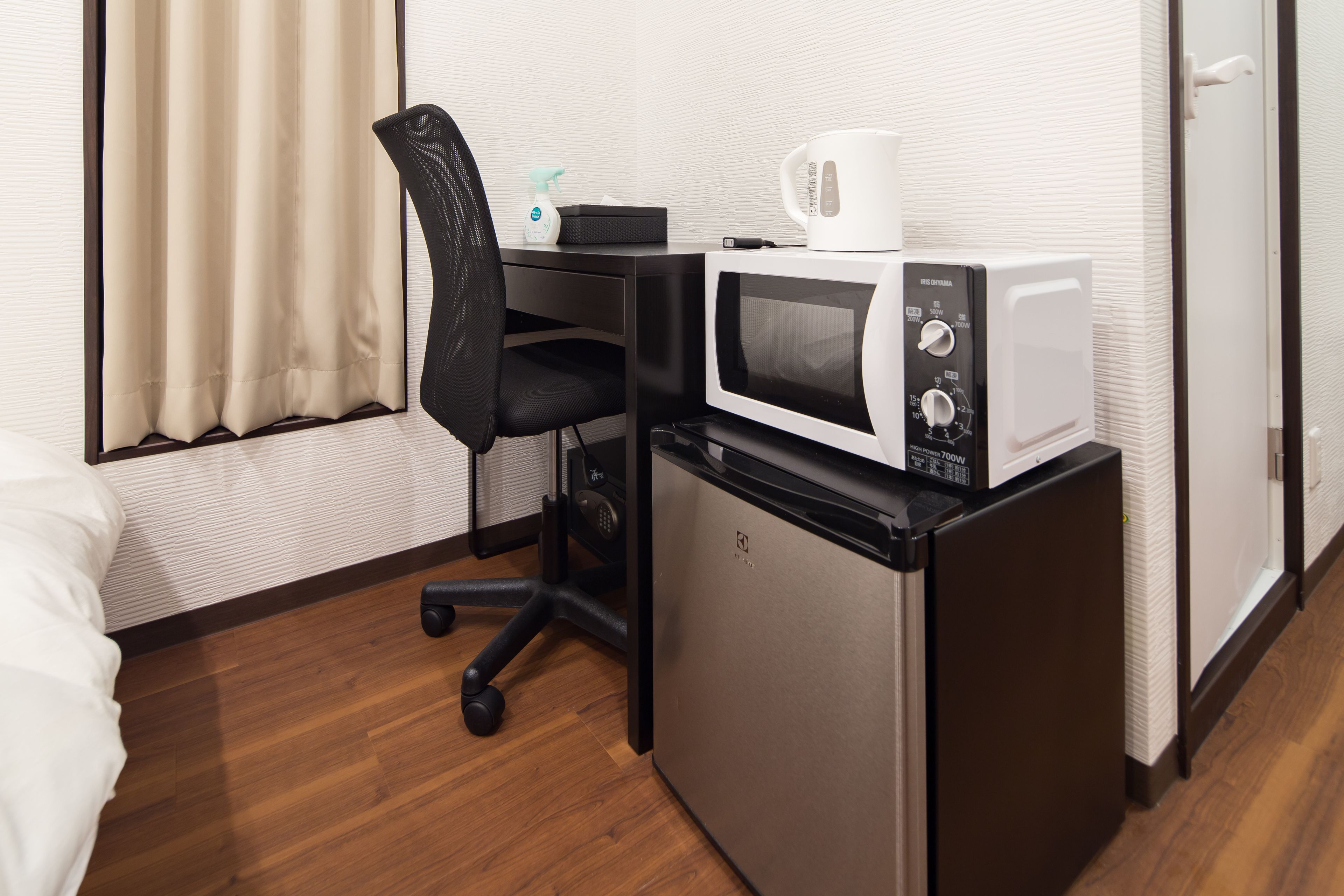 Uma cozinha compacta equipada com micro-ondas, cafeteira e mini-geladeira.