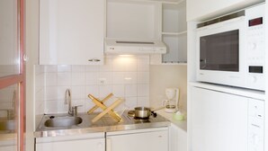 Uma cozinha compacta com pia, fogão, micro-ondas e máquina de lavar.
