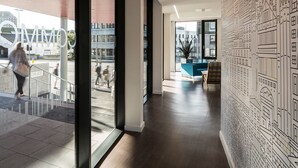 Um hall de hotel moderno com entrada de vidro, balcão de recepção azul e parede com padrão.