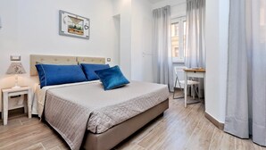 Um quarto com cama, mesa de cabeceira e escrivaninha.