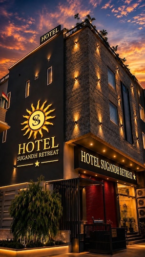 Um hotel com um logotipo de sol em destaque, uma placa com a inscrição 'Hotel Sugandh Retreat' e uma bandeira.