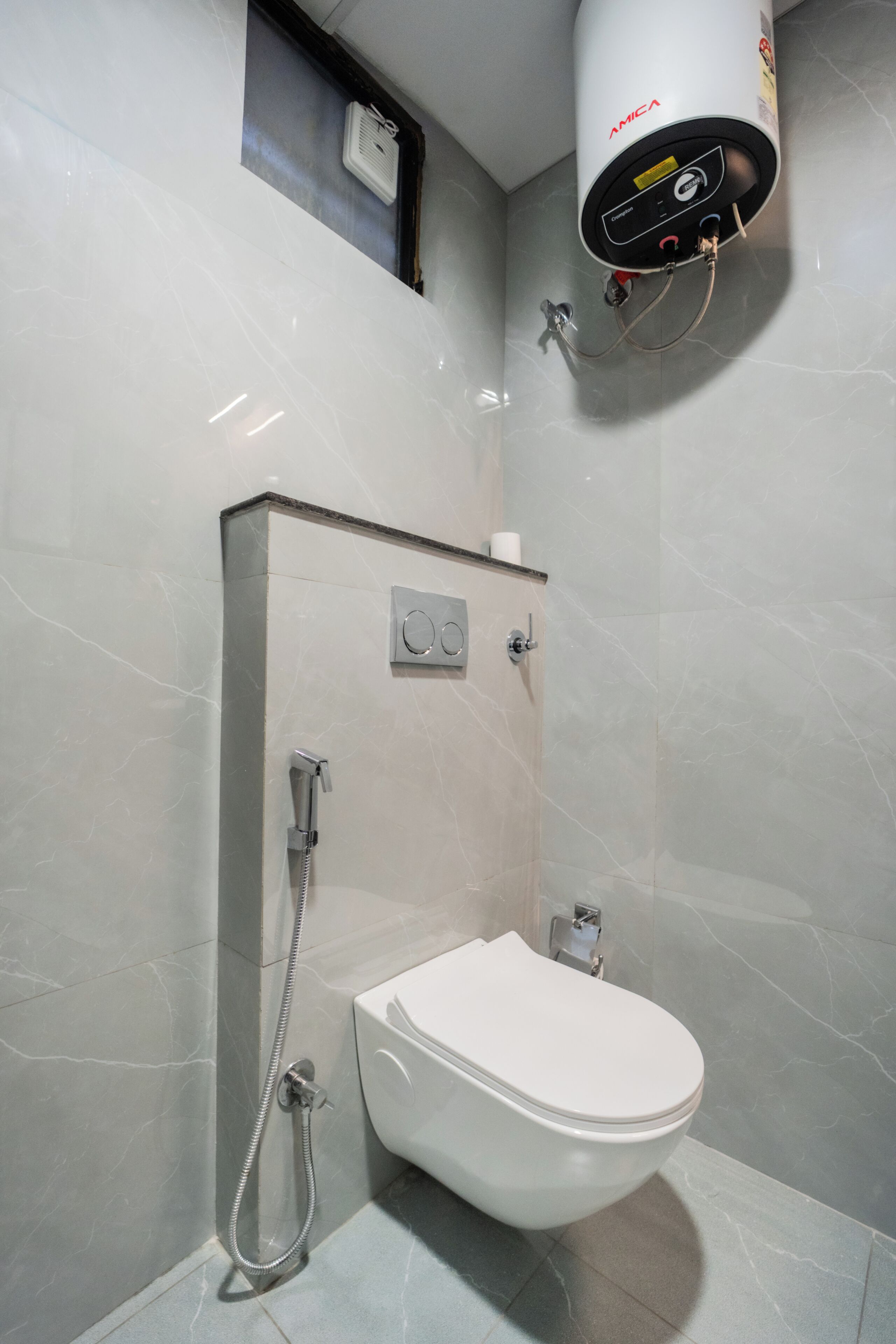 Uma casa de banho moderna com sanita, chuveiro e aquecedor fixo na parede.