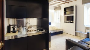 Uma cozinha compacta com eletrodomésticos modernos, uma sala de jantar com sofá e uma cama ao fundo.