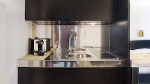 Uma cozinha moderna com armários pretos, eletrodomésticos de aço inoxidável e um vigamento de madeira.