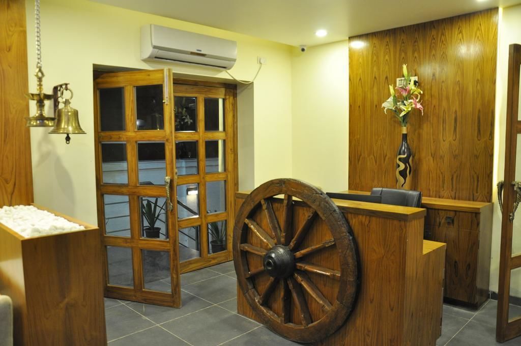 Uma área de recepção com uma mesa de madeira, uma grande roda de madeira e um vaso com planta.