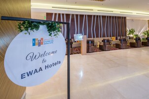 Uma área de recepção com uma placa de boas-vindas aos hóspedes do EWA Hotels.
