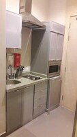 Cozinha compacta com pia, fogão, micro-ondas e armários.