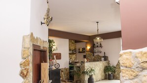 Interior com paredes de pedra, área de bar, mobiliário de madeira e plantas em vasos.