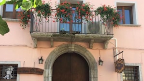 Um edifício com uma grande entrada em arco, uma varanda com flores vermelhas e uma placa com a inscrição 