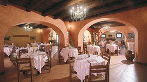 Um restaurante com várias mesas e cadeiras, tetos abobadados e lustres.