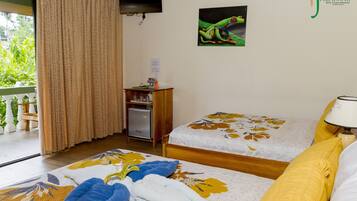 Quarto de hotel com duas camas, uma escrivaninha, uma televisão e uma janela com cortinas.